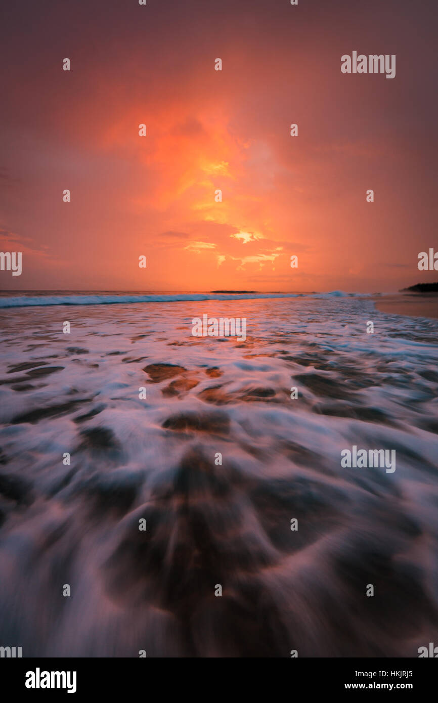 Sunset clouds and waves on empty beach Stock Photo - Alamy
