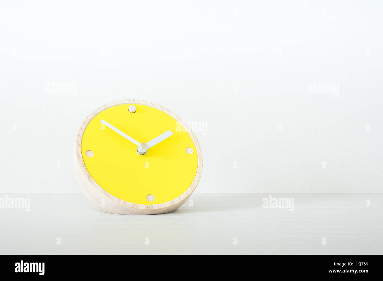 The yellow clock on wooden table standing out from white background ...