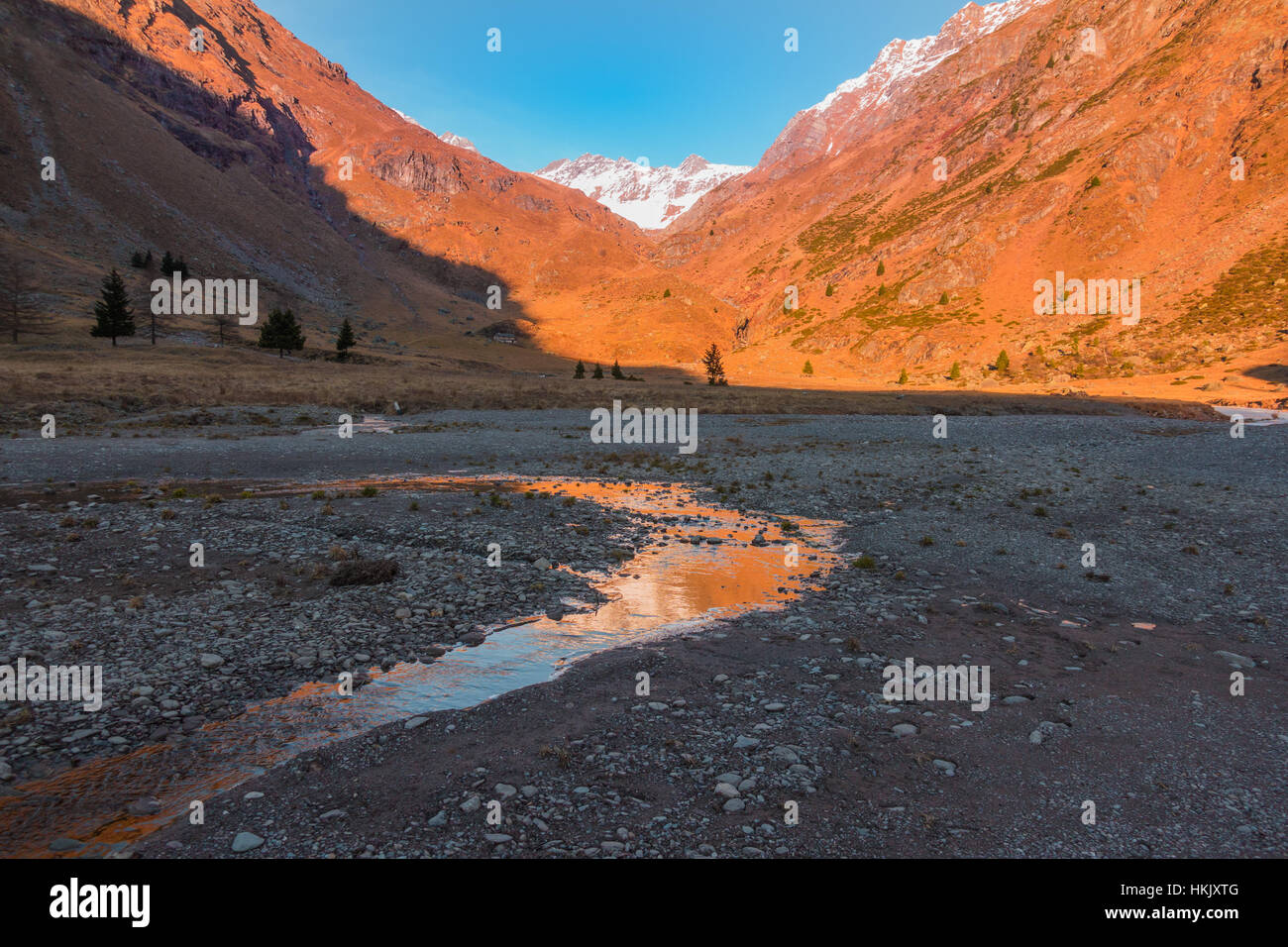 Small river and rocks and reflections in a valley between mountains at ...