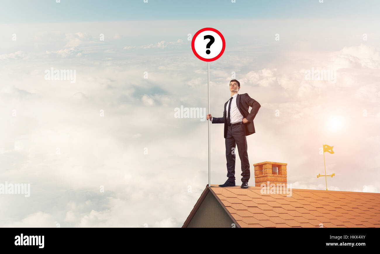 Businessman on brick house roof showing banner with question mar Stock ...