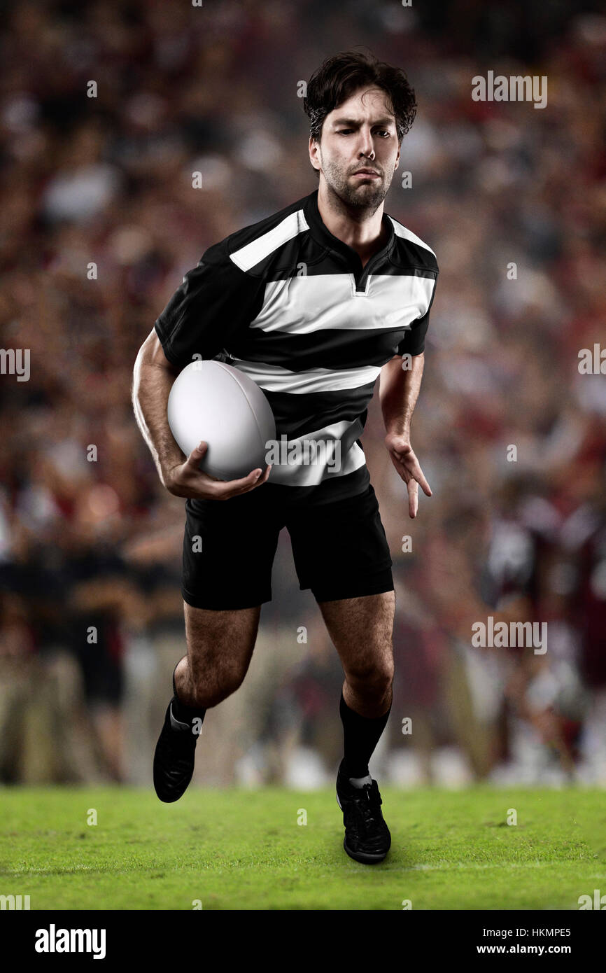 Rugby player in a black and white uniform running on a stadium Stock ...
