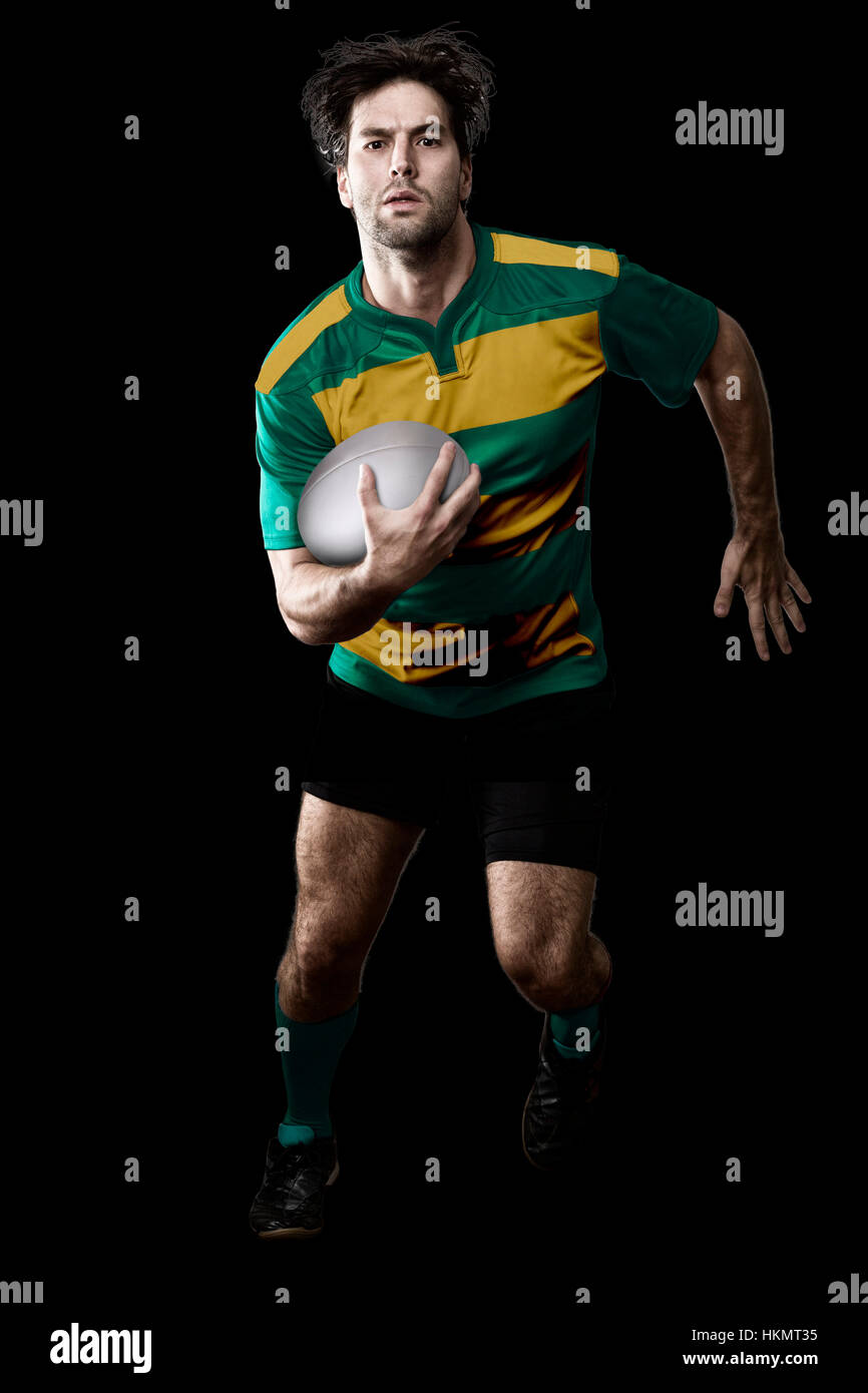 Rugby player in a green and gold uniform running. Black Background ...