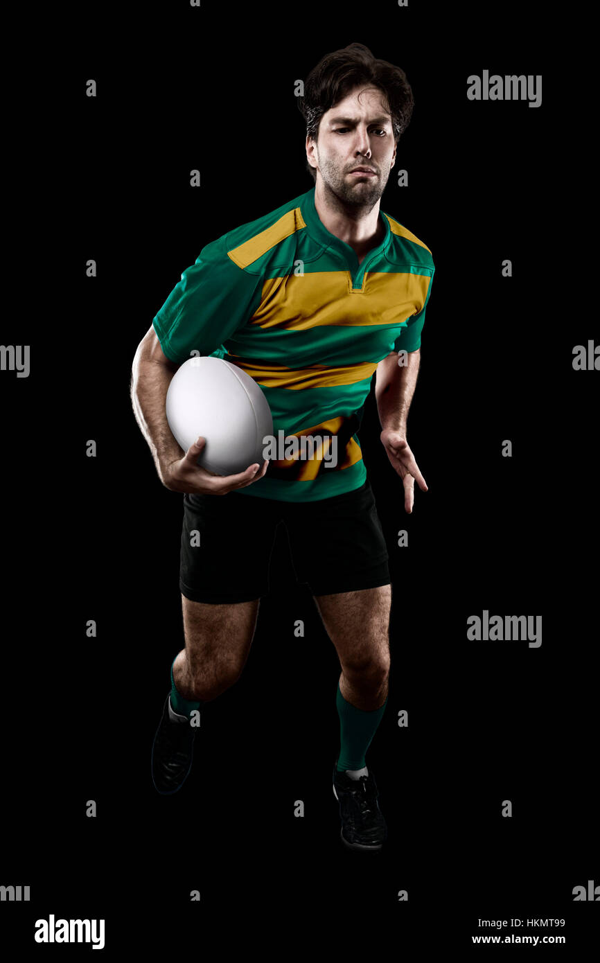 Rugby player in a green and gold uniform running. Black Background ...