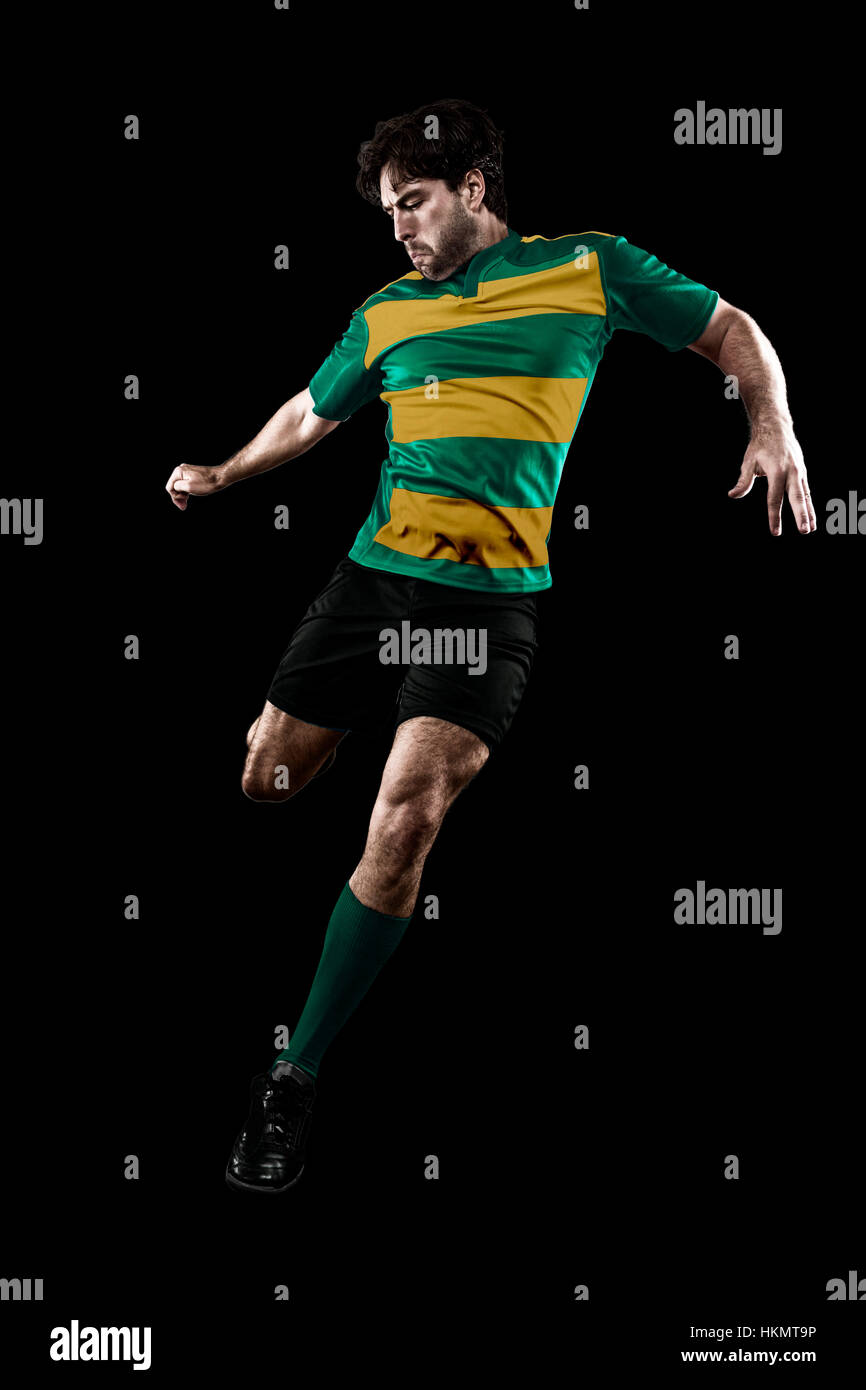 Rugby player in a green and gold uniform kicking. Black Background ...