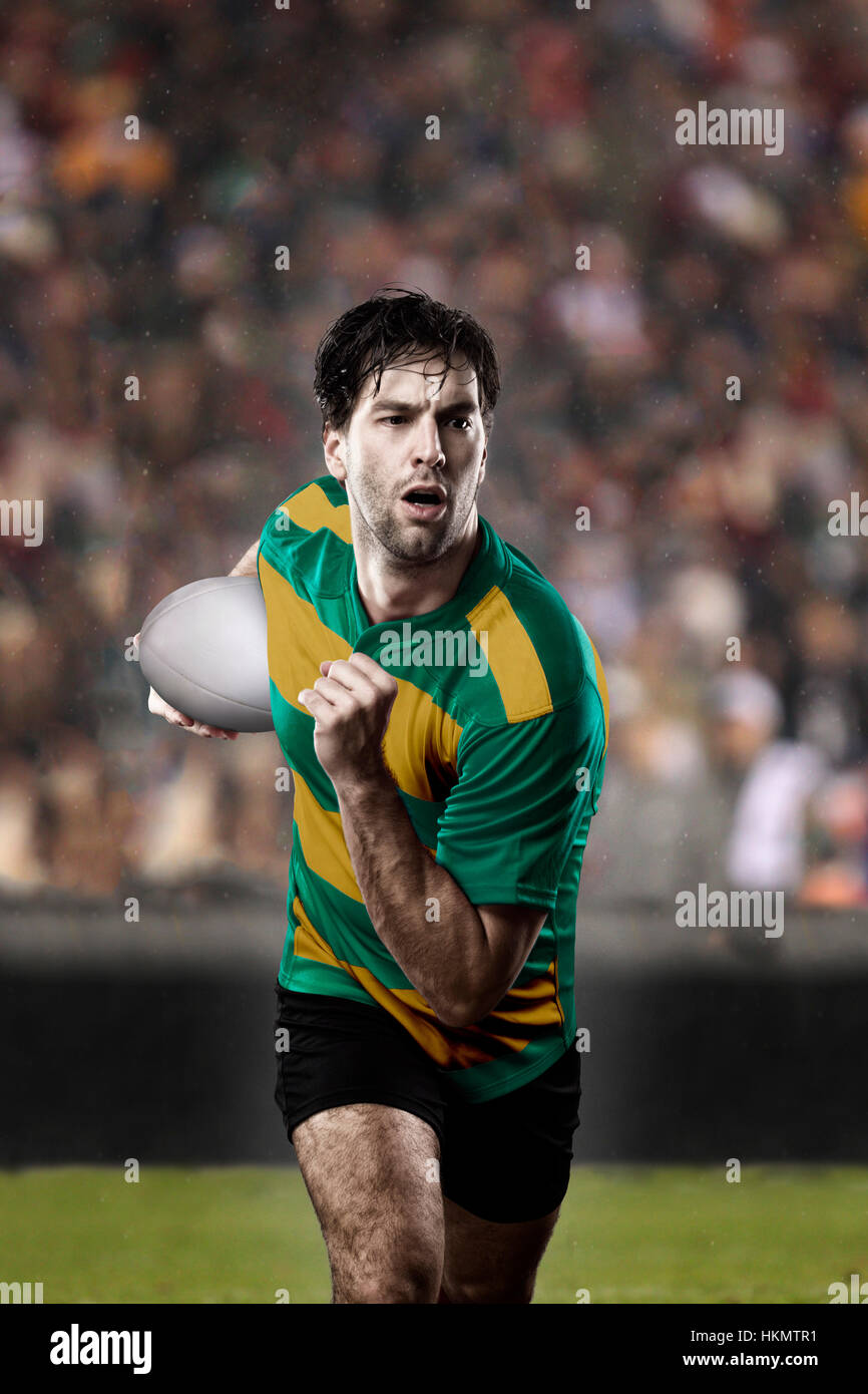 Rugby player in a green and gold uniform running on a stadium Stock ...