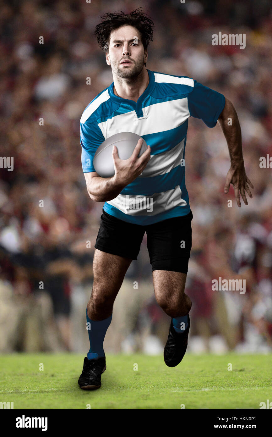 Rugby player in a blue uniform running on a stadium Stock Photo - Alamy