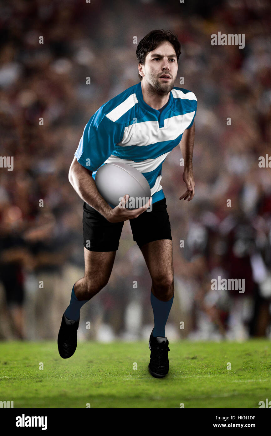 Rugby player in a blue uniform running on a stadium Stock Photo - Alamy