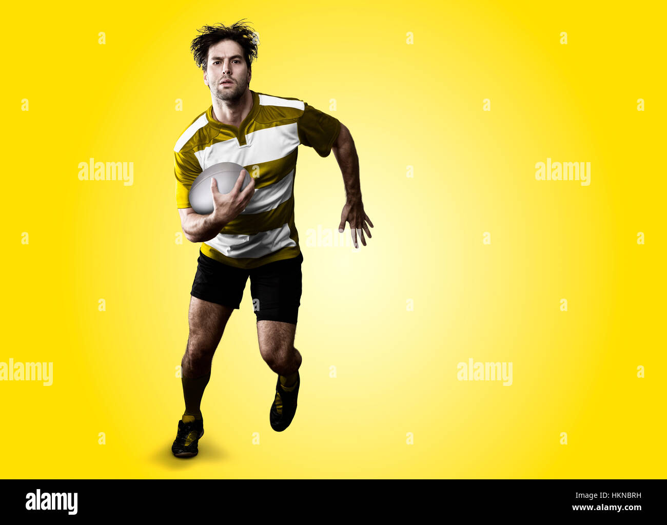 Rugby player in a yellow uniform running on a yellow background Stock ...