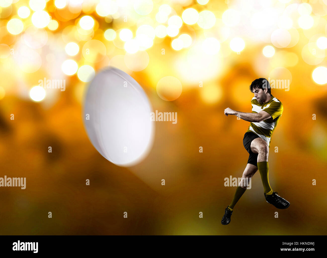 Rugby player in a yellow uniform kicking a ball on a yellow lights ...