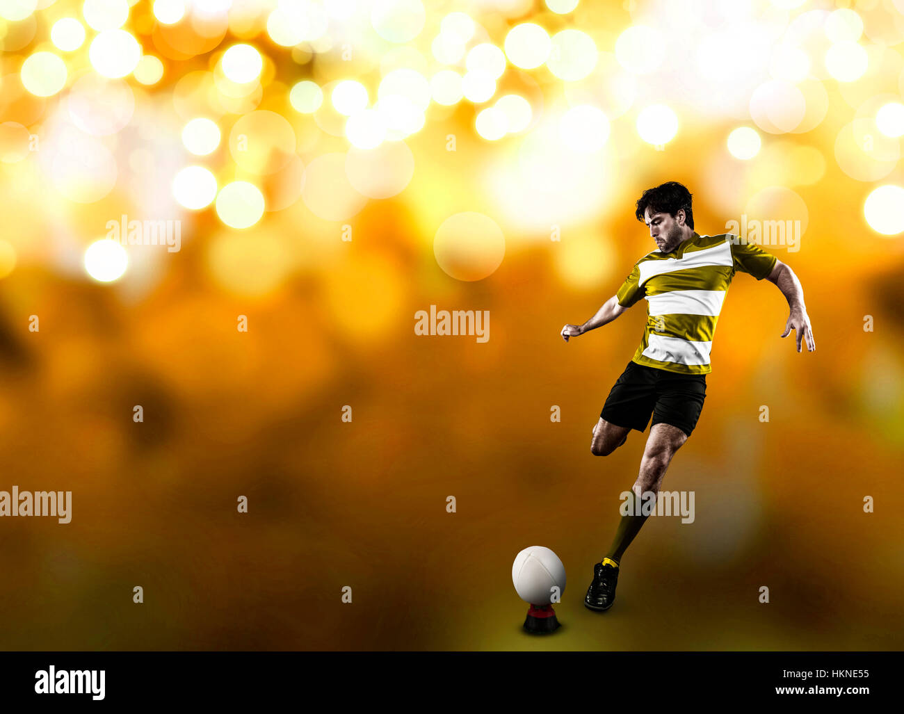 Rugby player in a yellow uniform kicking a ball on a yellow lights ...