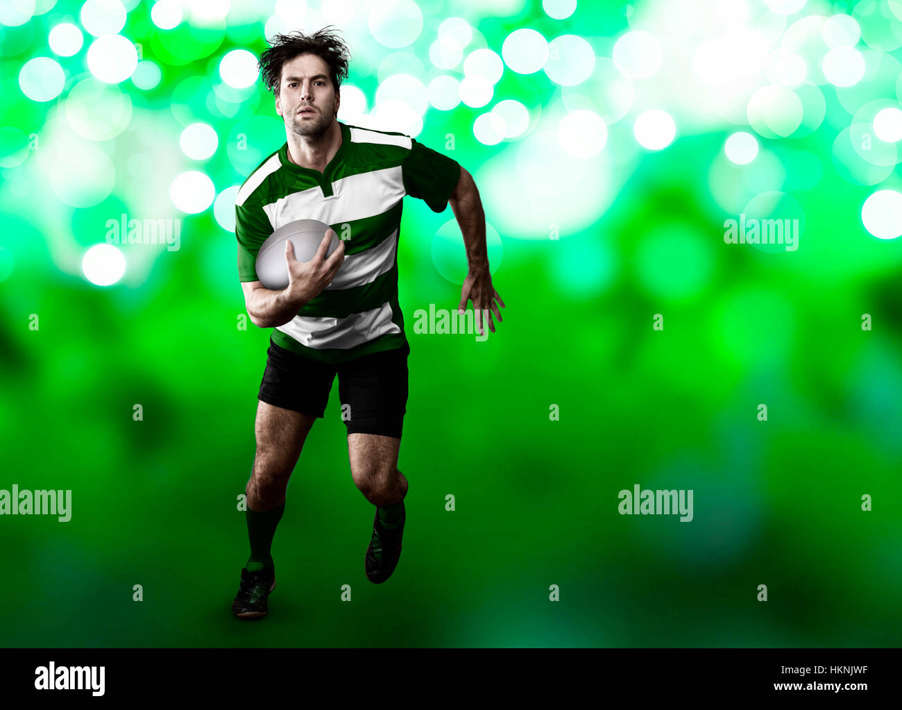 Rugby player in a green uniform running on a green lights backgrond ...