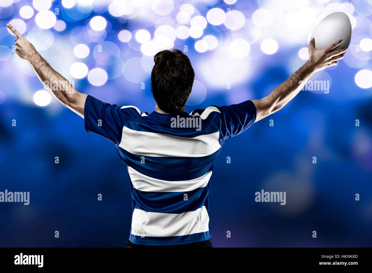 Rugby player in a blue uniform celebrating on a blue lights background ...