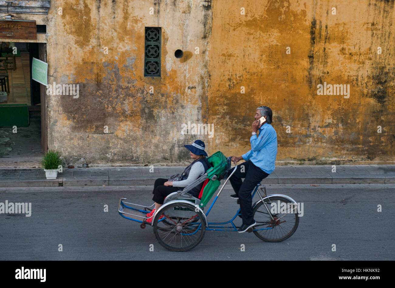 Cyclo driver and yellow walls in the picturesque old town of Hoi An ...