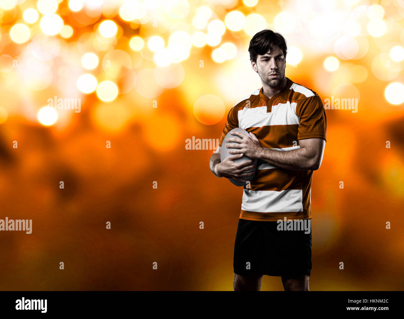 Rugby player in a orange uniform on a orange lights background Stock ...