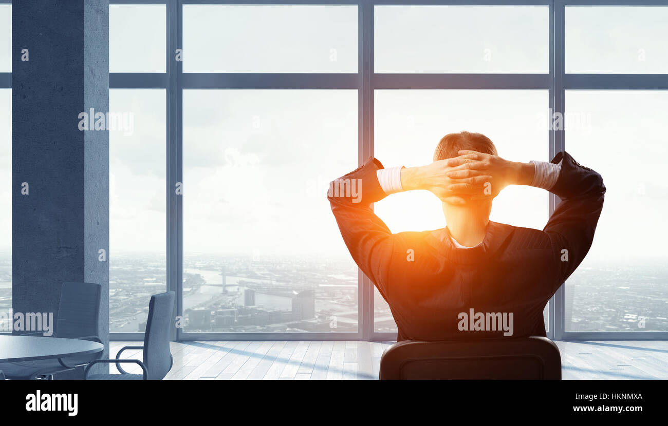 Back view of relaxed businessman sitting on chair with hands on nape ...