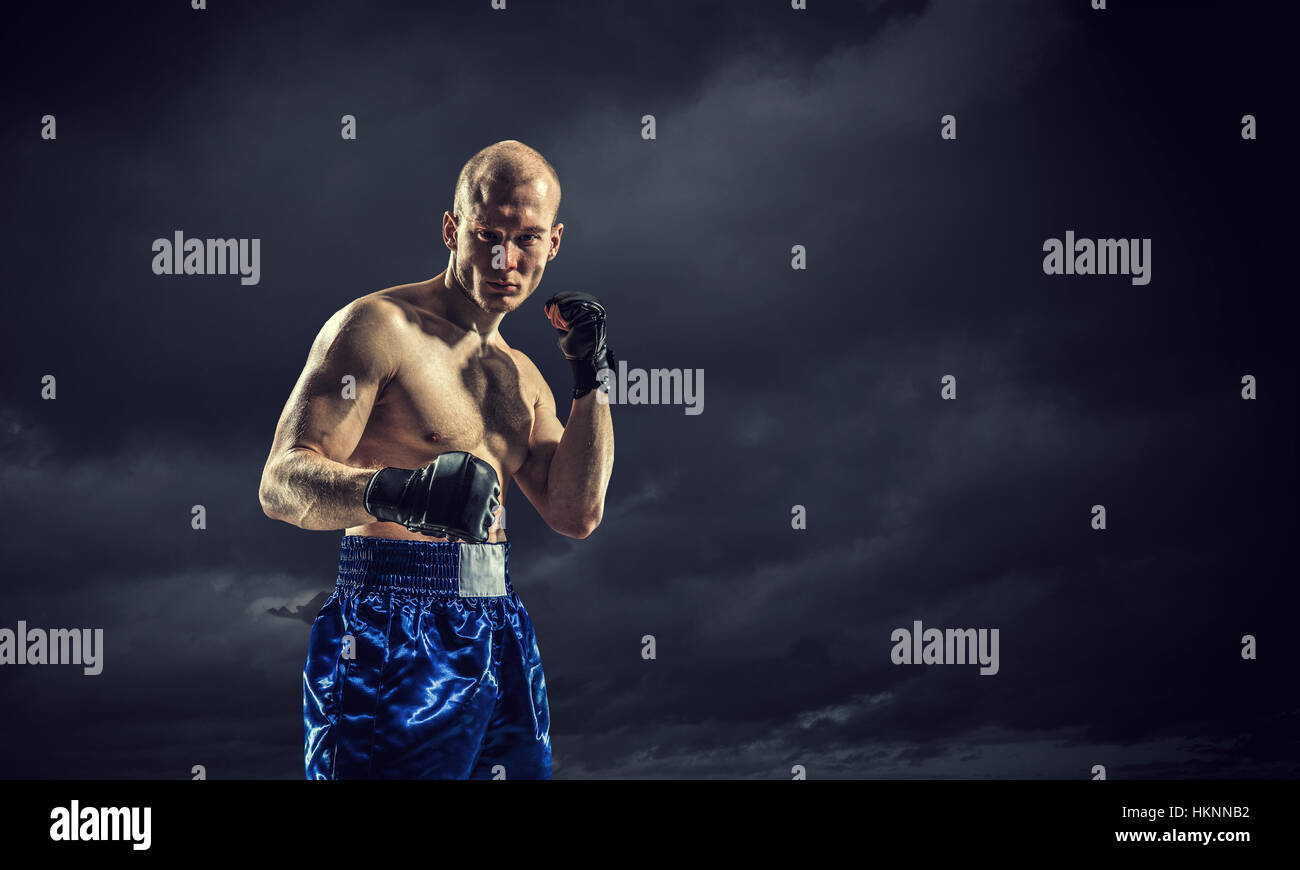 Strong fighter in shorts against dark sky background Stock Photo - Alamy
