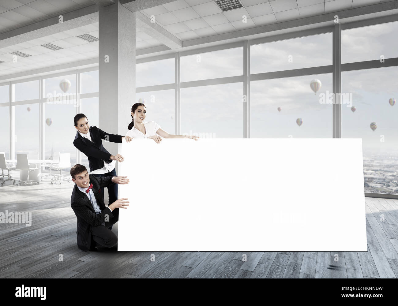 Group of young business people holding big blank banner. Mixed media ...