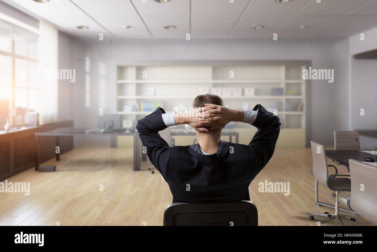Back view of relaxed businessman sitting on chair with hands on nape ...