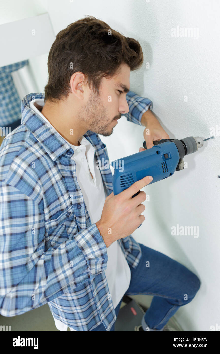 male builder drilling holes in wall at construction site Stock Photo ...
