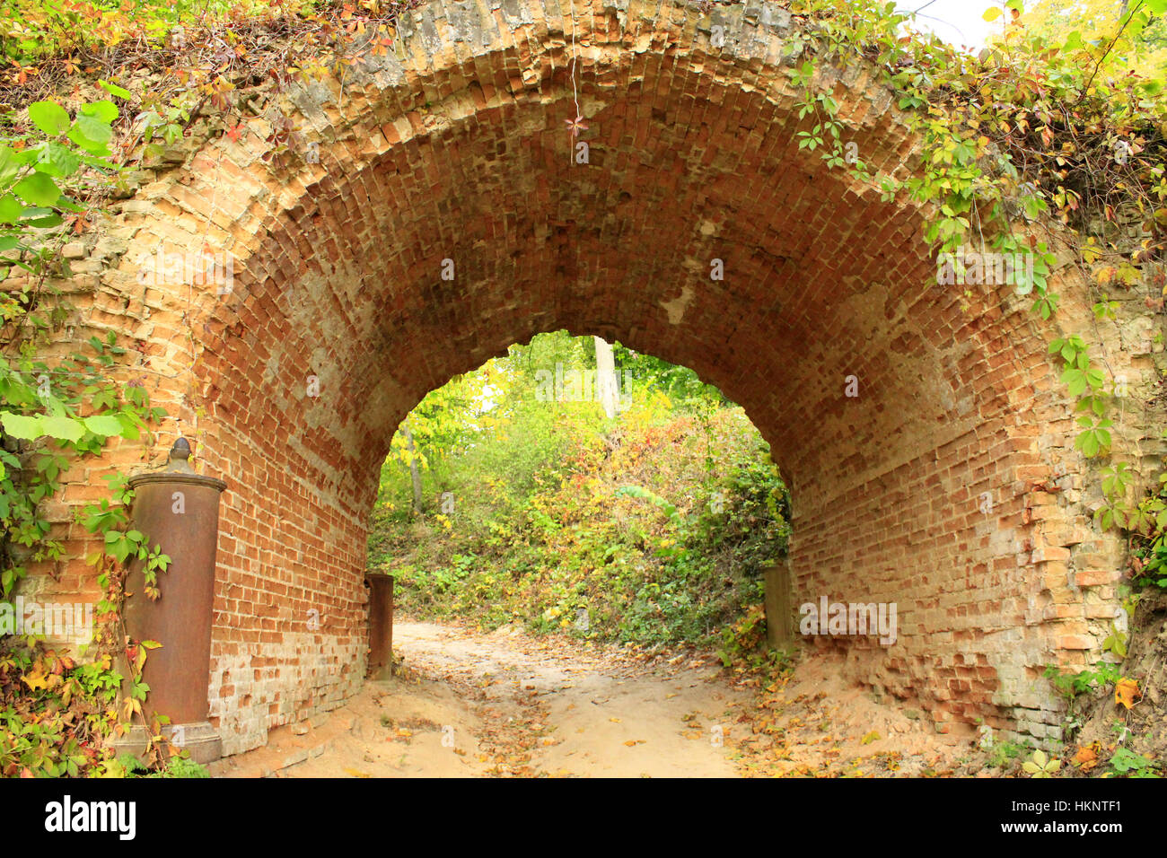 sandy road under historical arch from red bricks in Kachanivka park ...