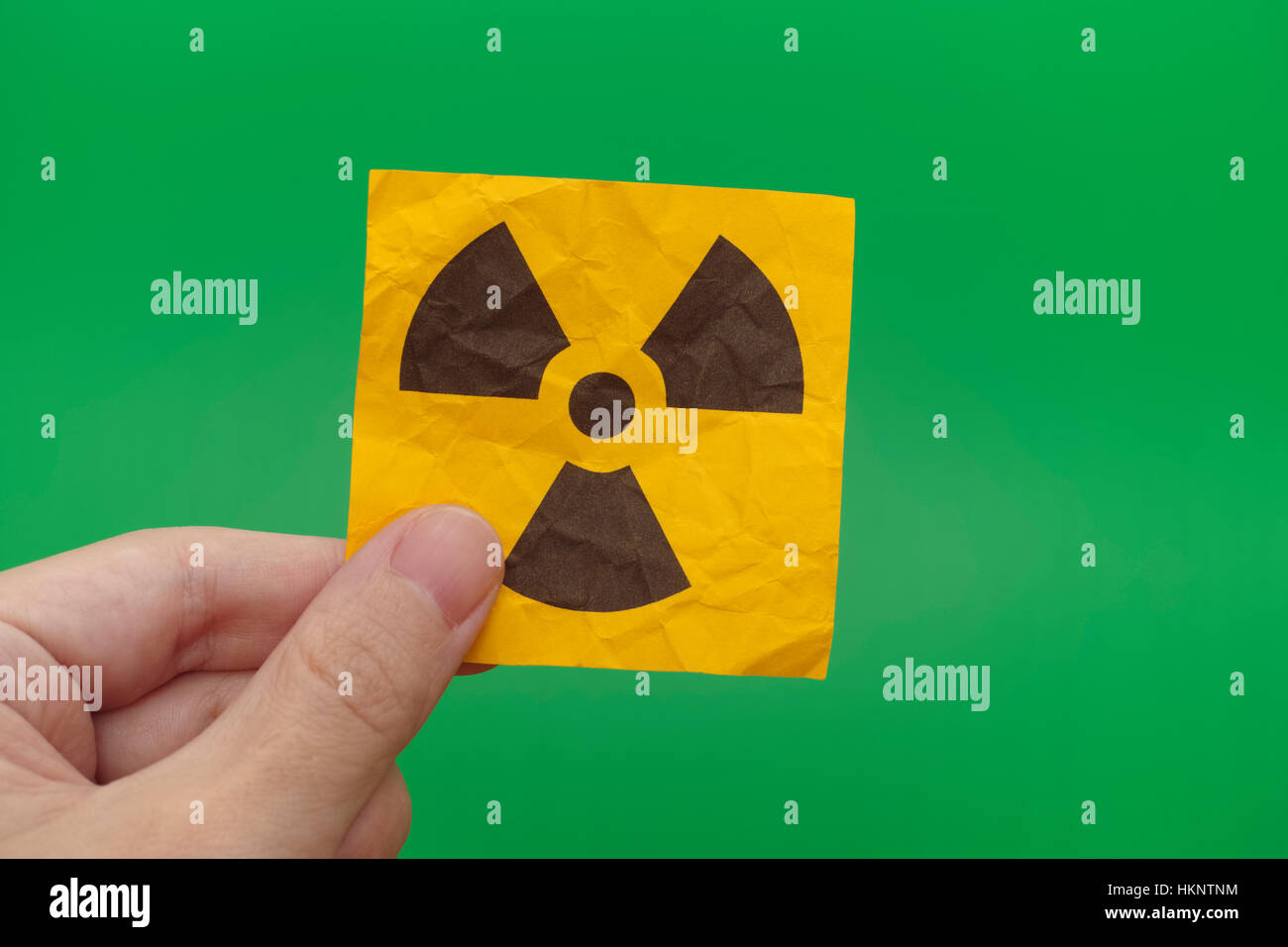 Person holding Radiation warning sign in his hand against green ...