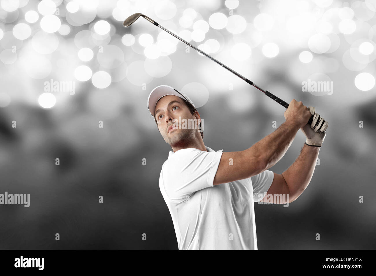 Golf Player in a white shirt taking a swing, on a white lights ...