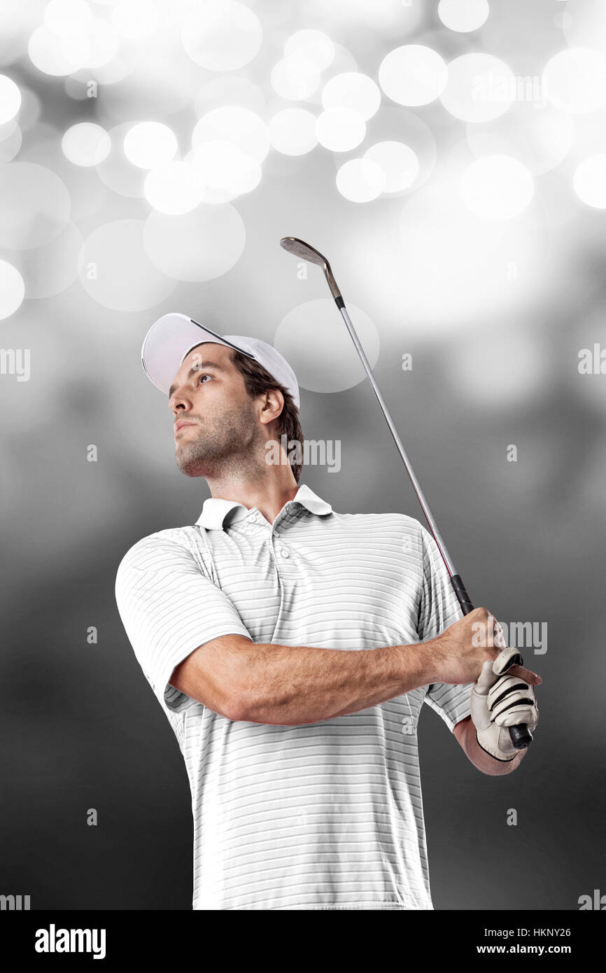 Golf Player in a white shirt taking a swing, on a white lights ...