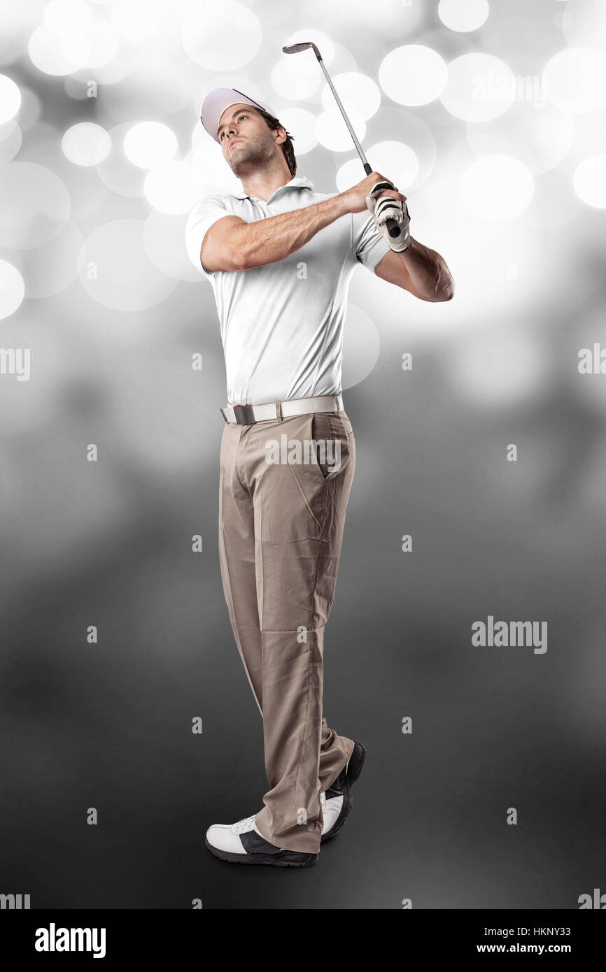 Golf Player in a white shirt taking a swing, on a white lights ...