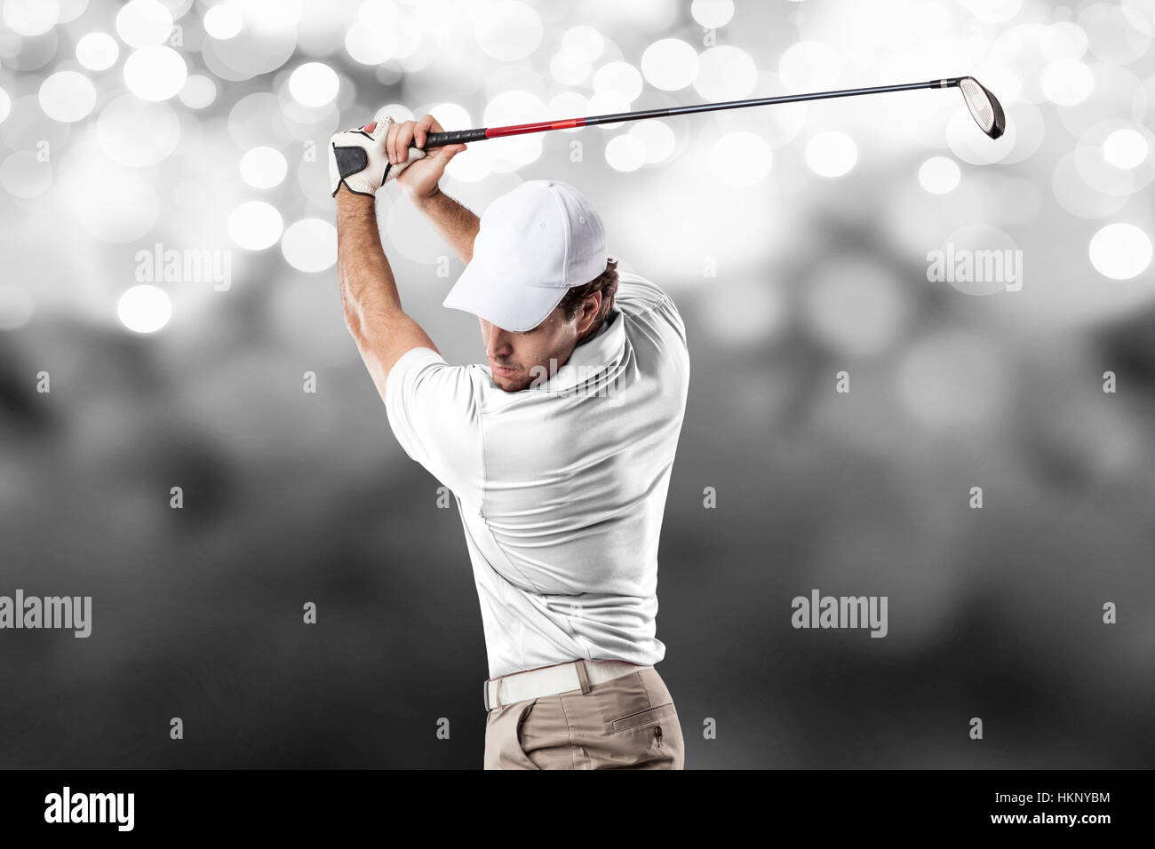 Golf Player in a white shirt taking a swing, on a white lights ...