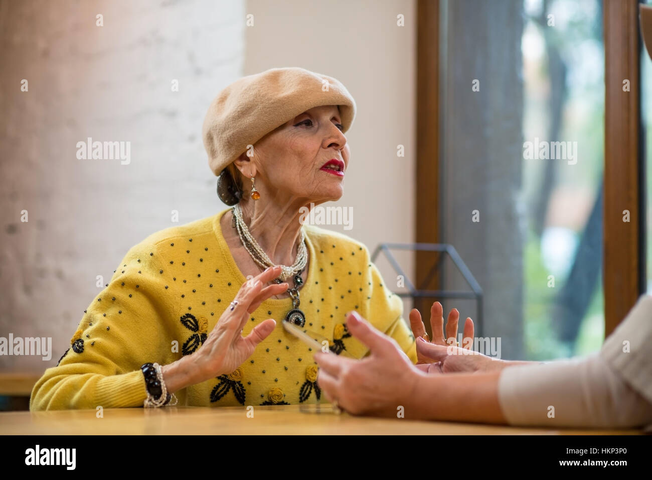 Elderly woman talking at table Stock Photo - Alamy