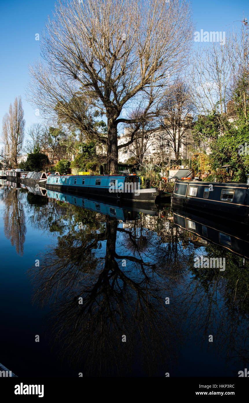 Boat, trees, birds are reflecting over Regent's Canal while people ...