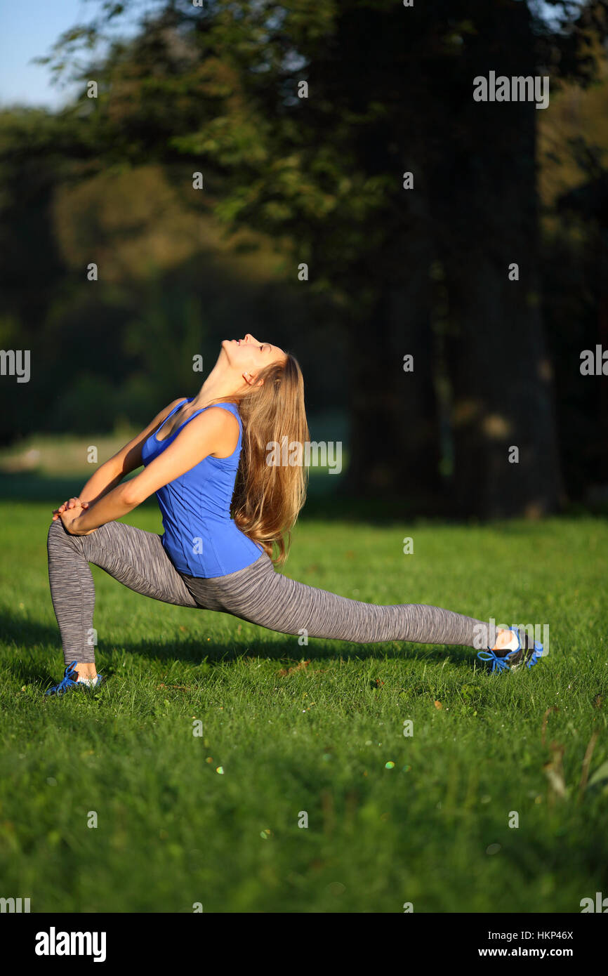 Young woman with long hair making a lunge with his head thrown back ...