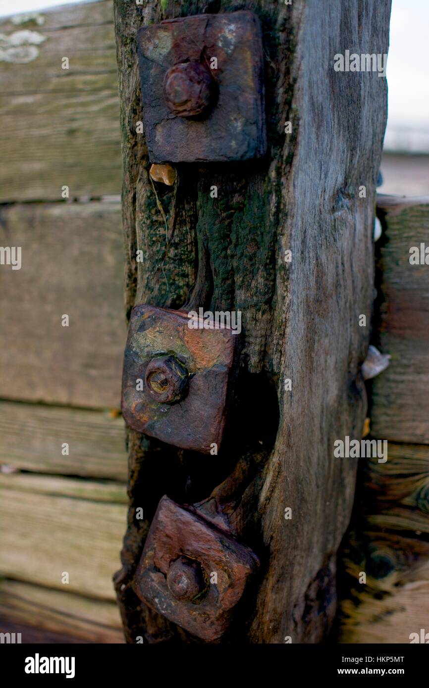Seaside Rusting bolts and wooden posts Stock Photo - Alamy