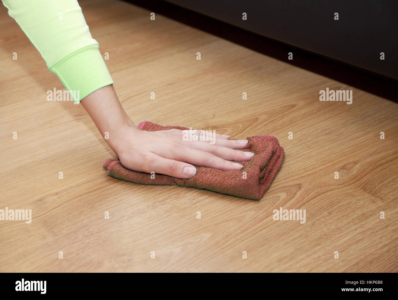 woman's hand cleaning the wooden floor with a brown floorcloth closeup ...