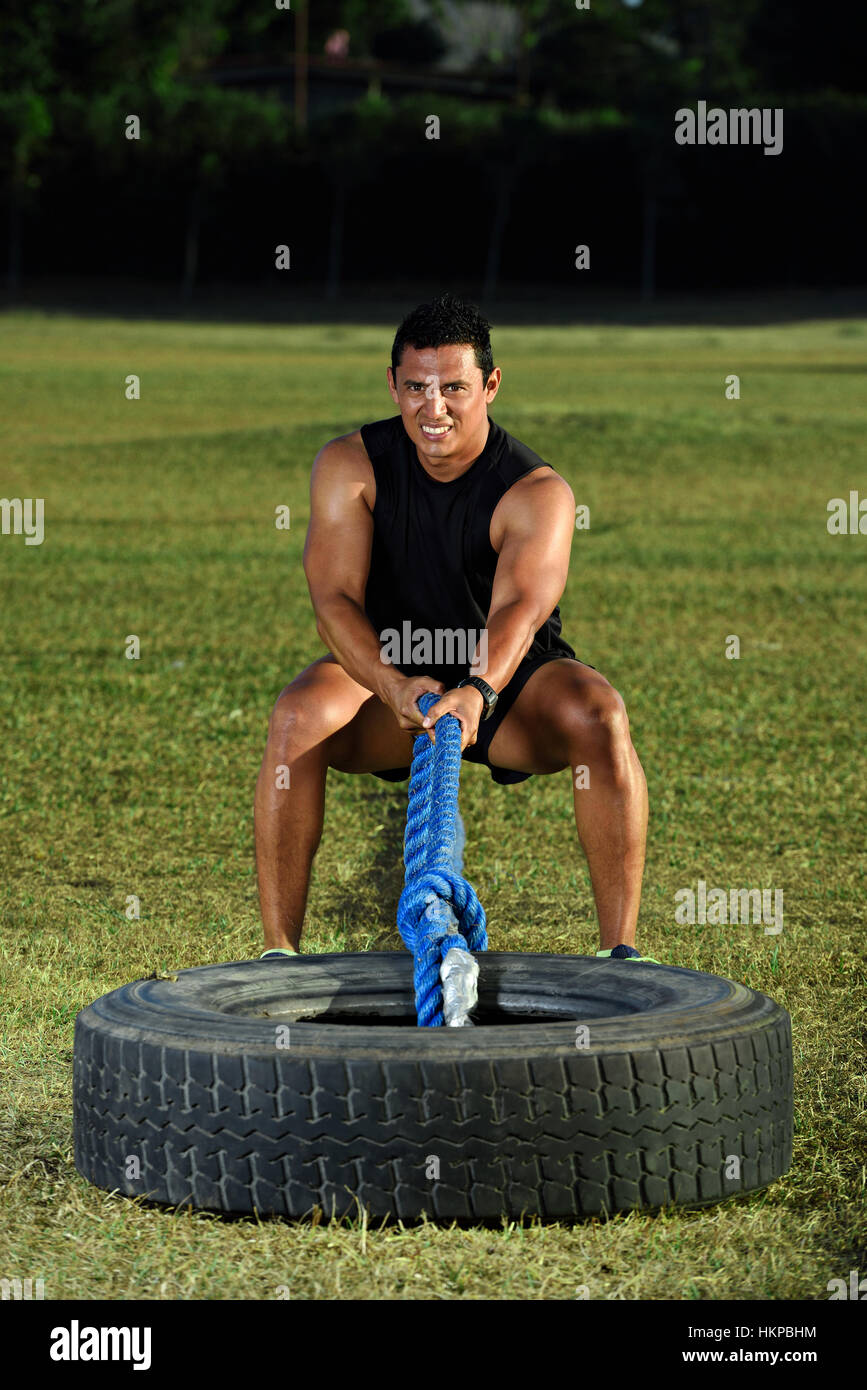 sporty guy pull tire on green lawn grass Stock Photo - Alamy
