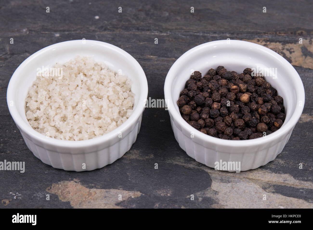 Course gray salt and peppercorns in small ramekins on gray slate Stock ...