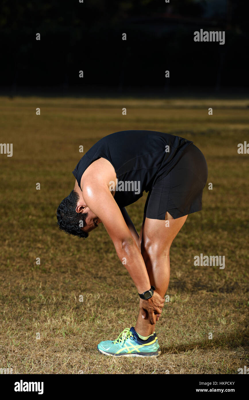 sport man stretching his back on park grass Stock Photo - Alamy
