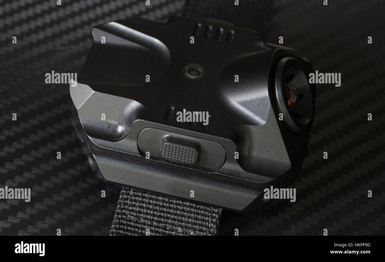 Side view of a tactical flashlight and activation button that is worn ...