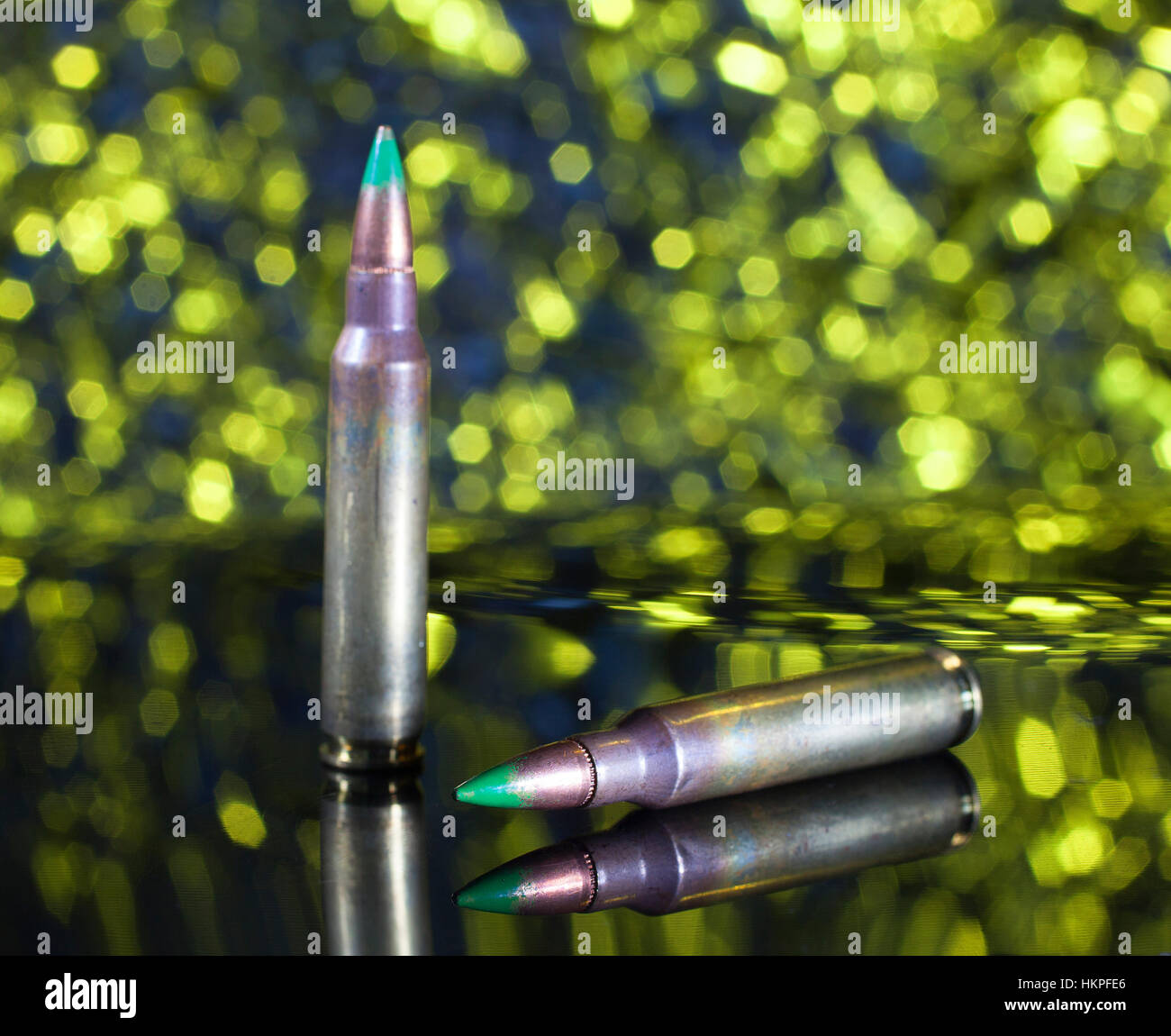 Two cartridges with green tips for a rifle with a bright yellow ...
