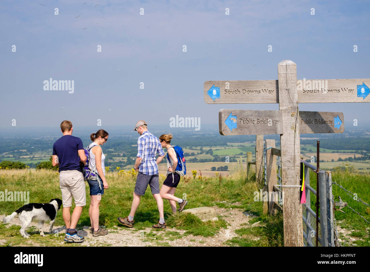 Footpath signpost and friends walking with a dog on South Downs Way in ...