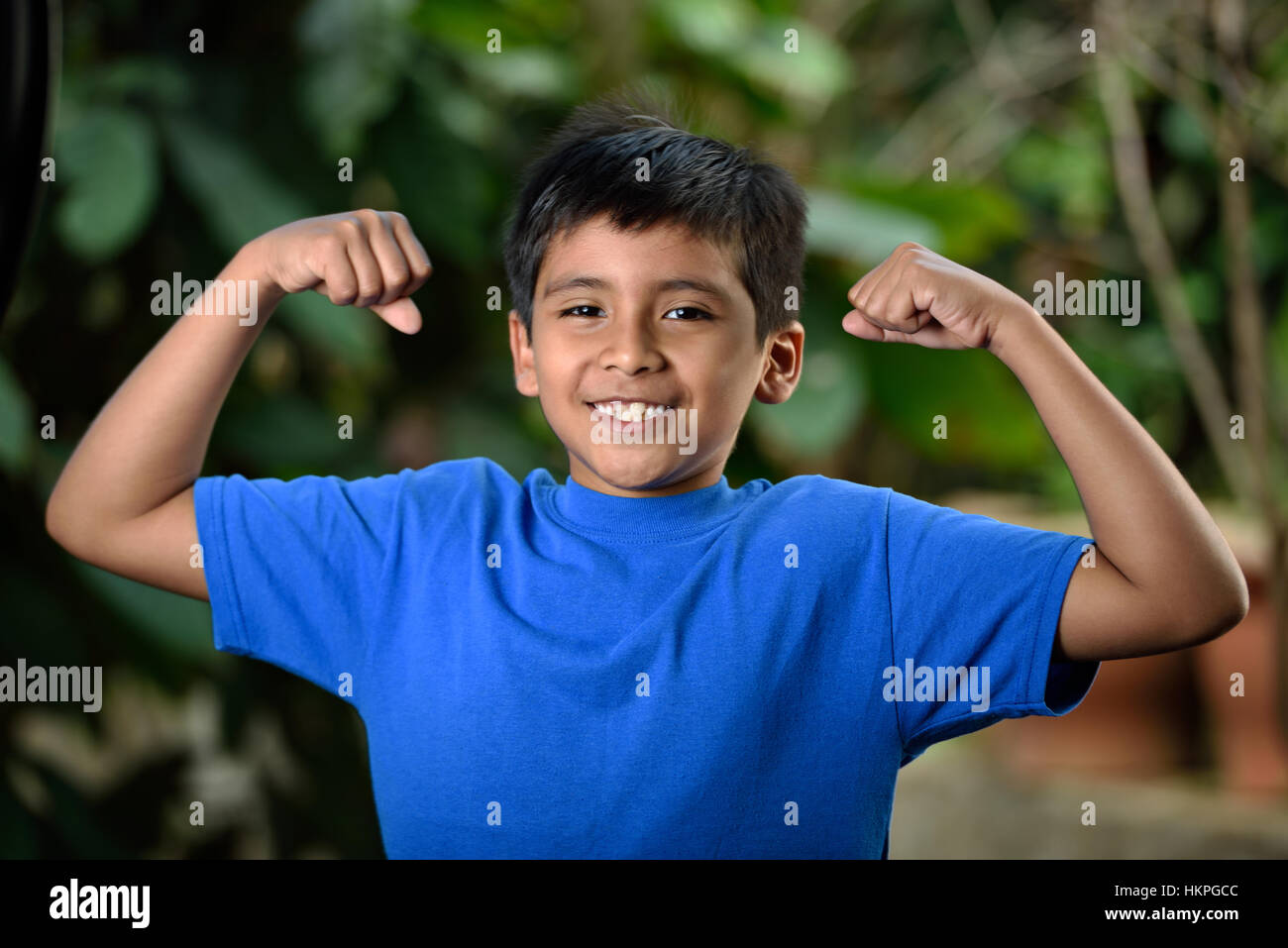 latino boy show muscles in green nature Stock Photo - Alamy