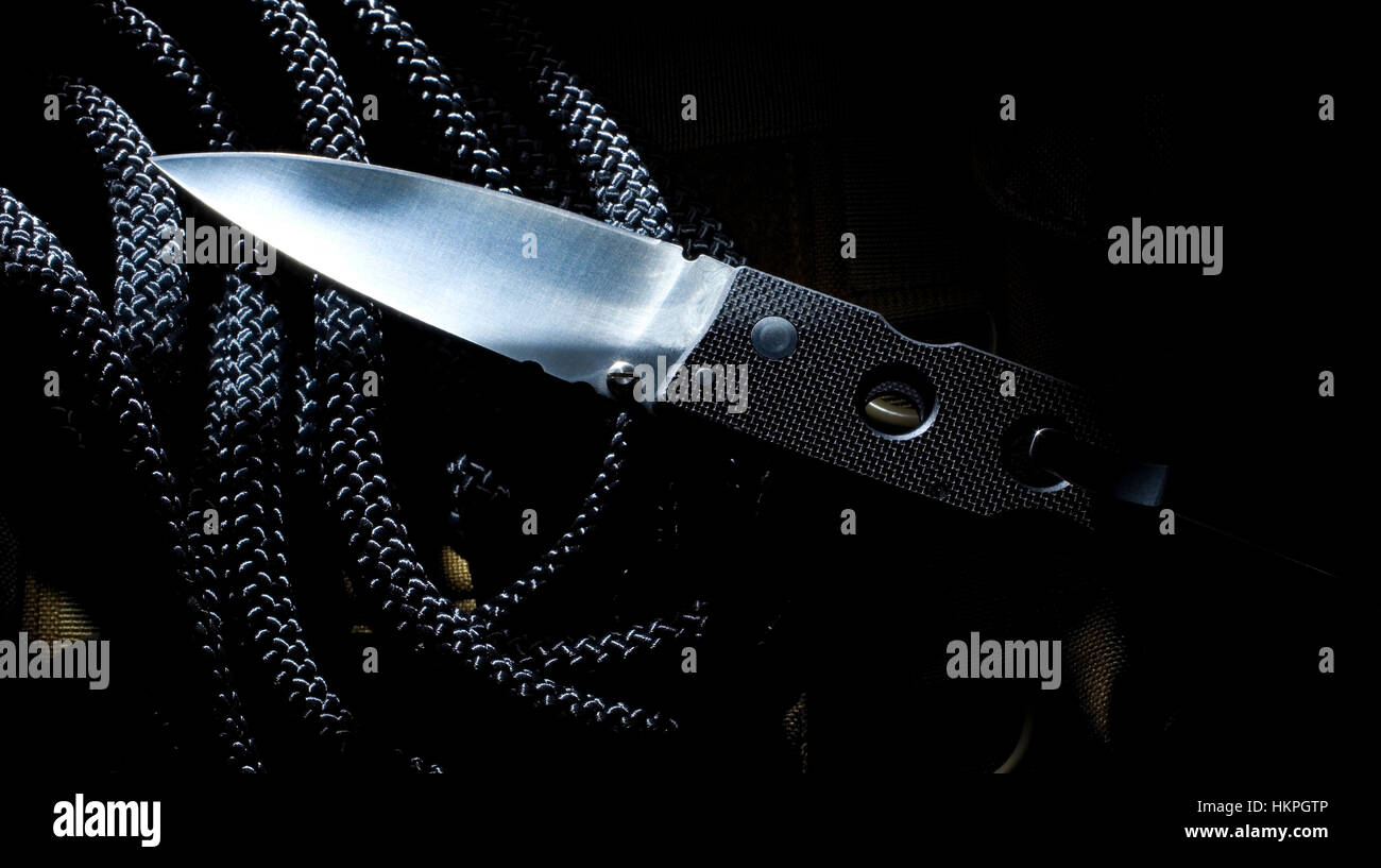 Folding self defense knife that is on a black rope Stock Photo - Alamy