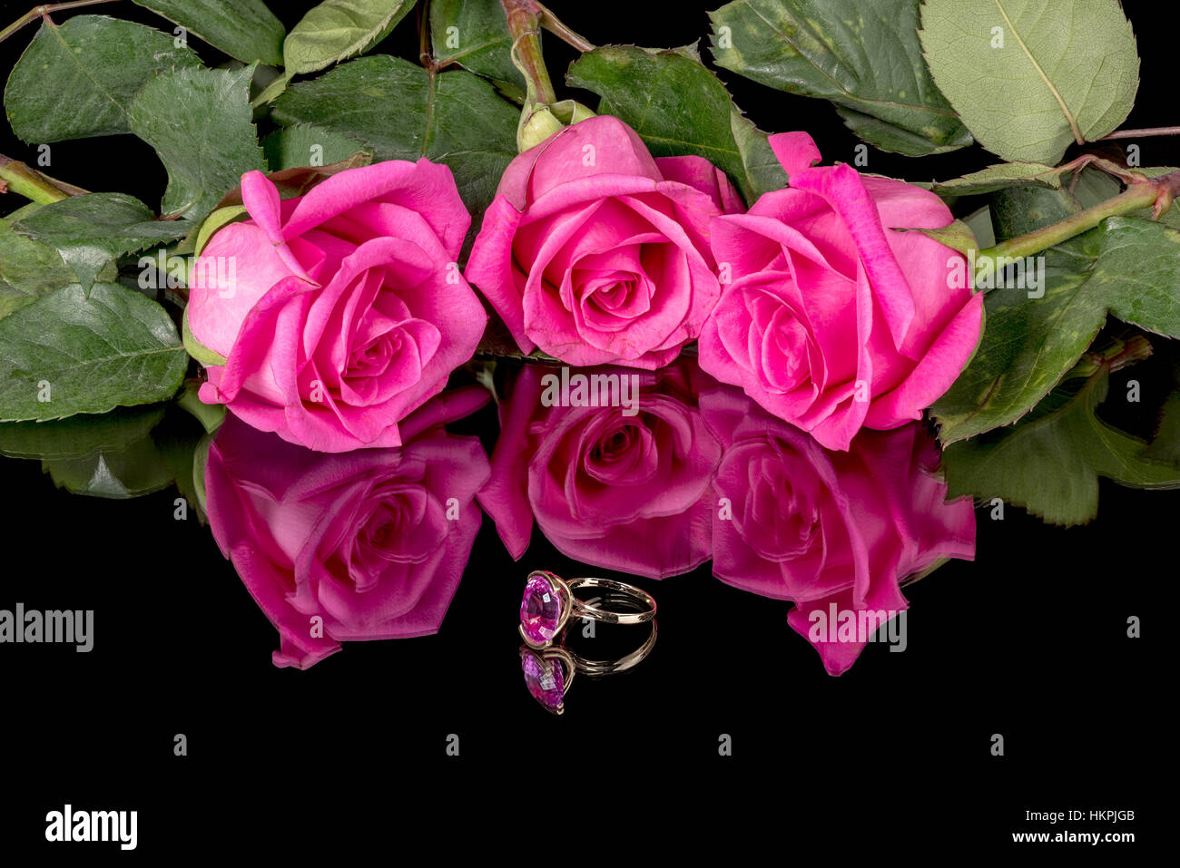 Three roses that are pink and a ring of the same color Stock Photo - Alamy