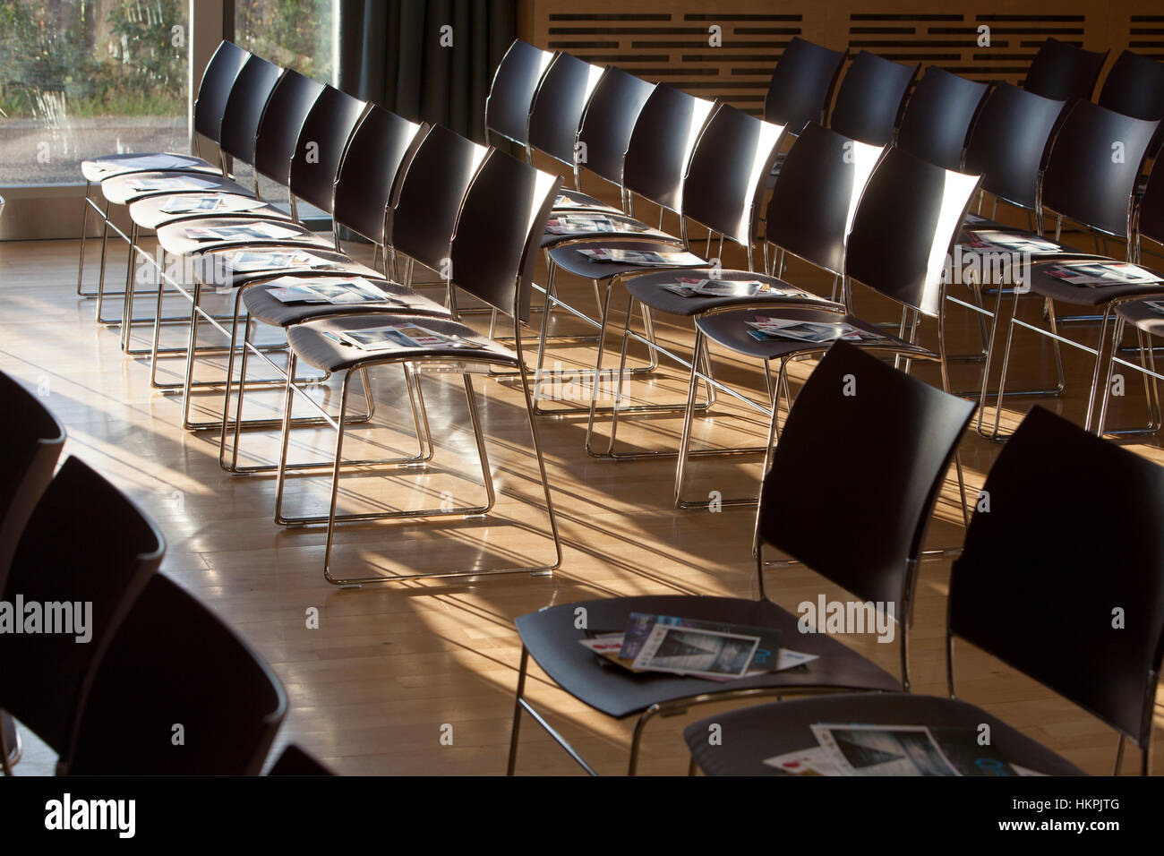 Strong window light plays on chairs set up in a hall for a conference ...