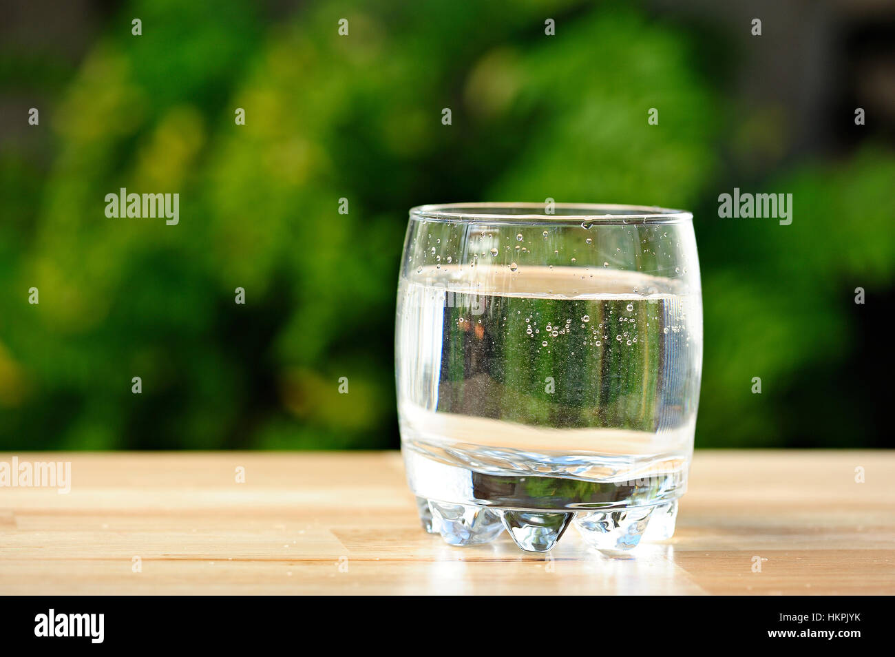 glass with sparkle water on table green park background Stock Photo - Alamy