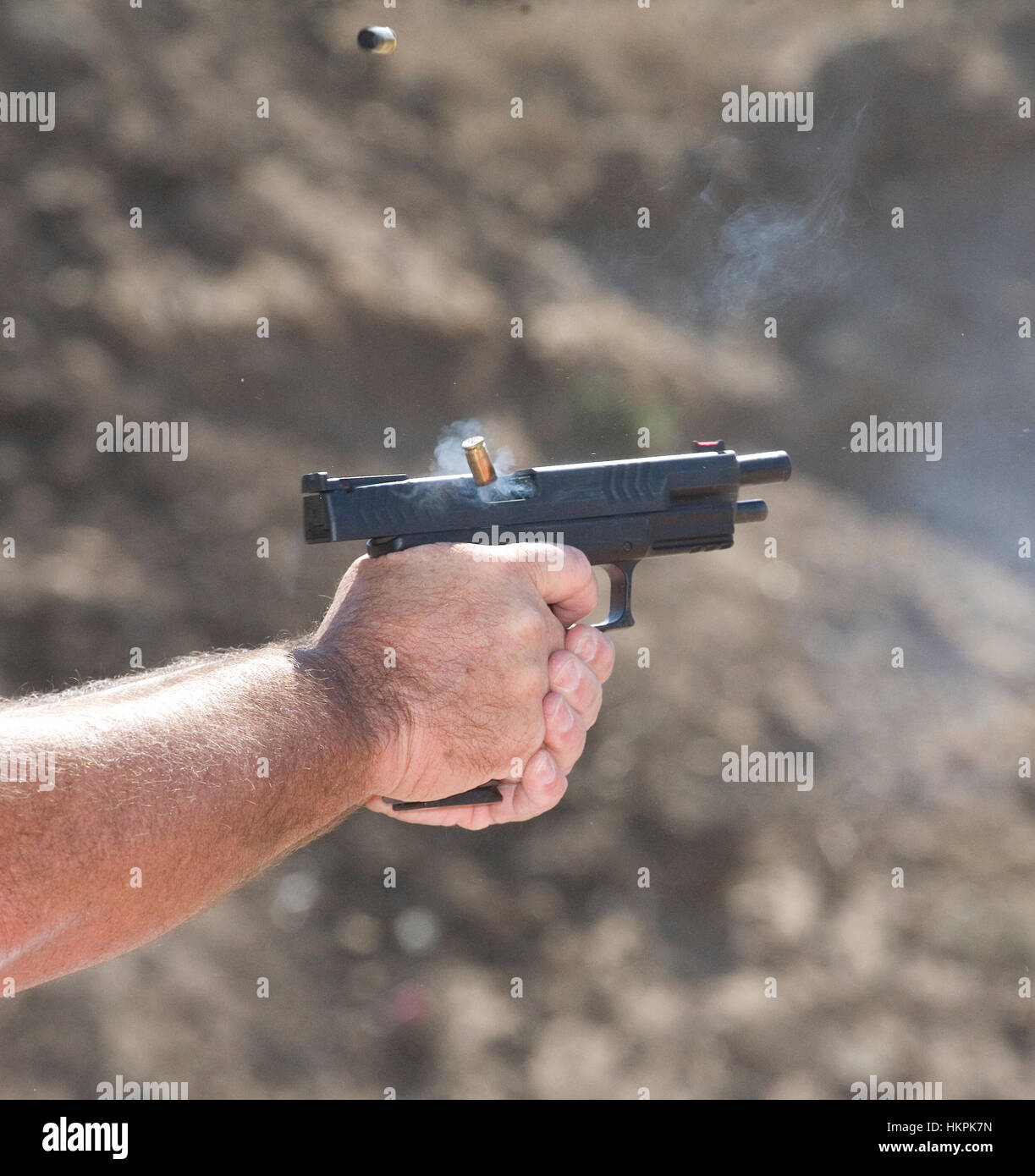 Two brass casing fly from a handgun that is going back into battery ...