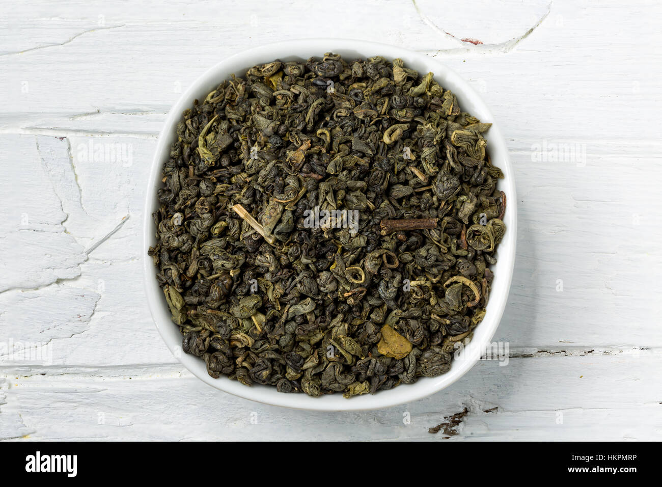 Dried green tea leaves gunpowder in white bowl on white wooden ...