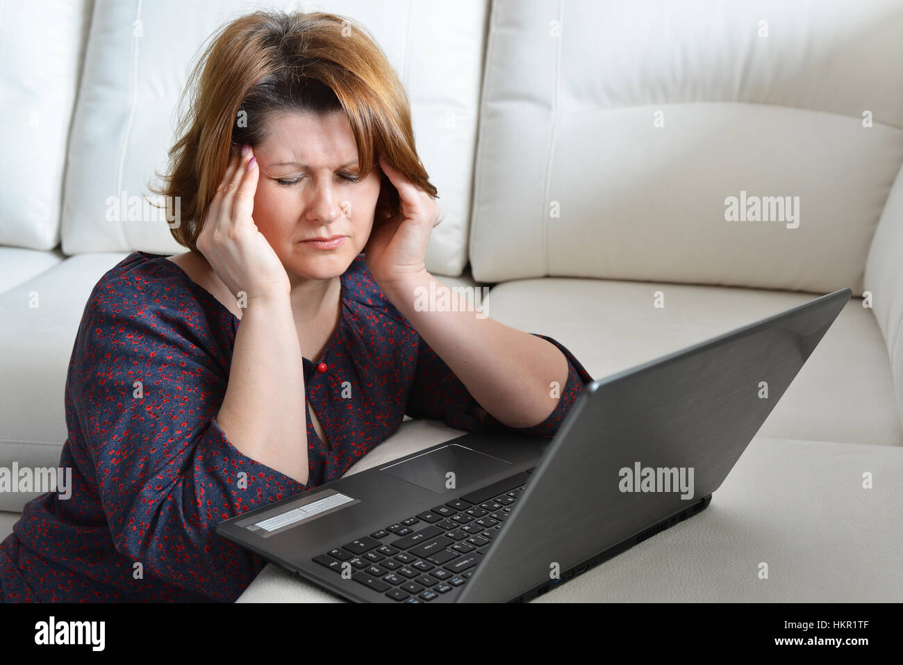 Woman with headache uses a computer at home Stock Photo - Alamy