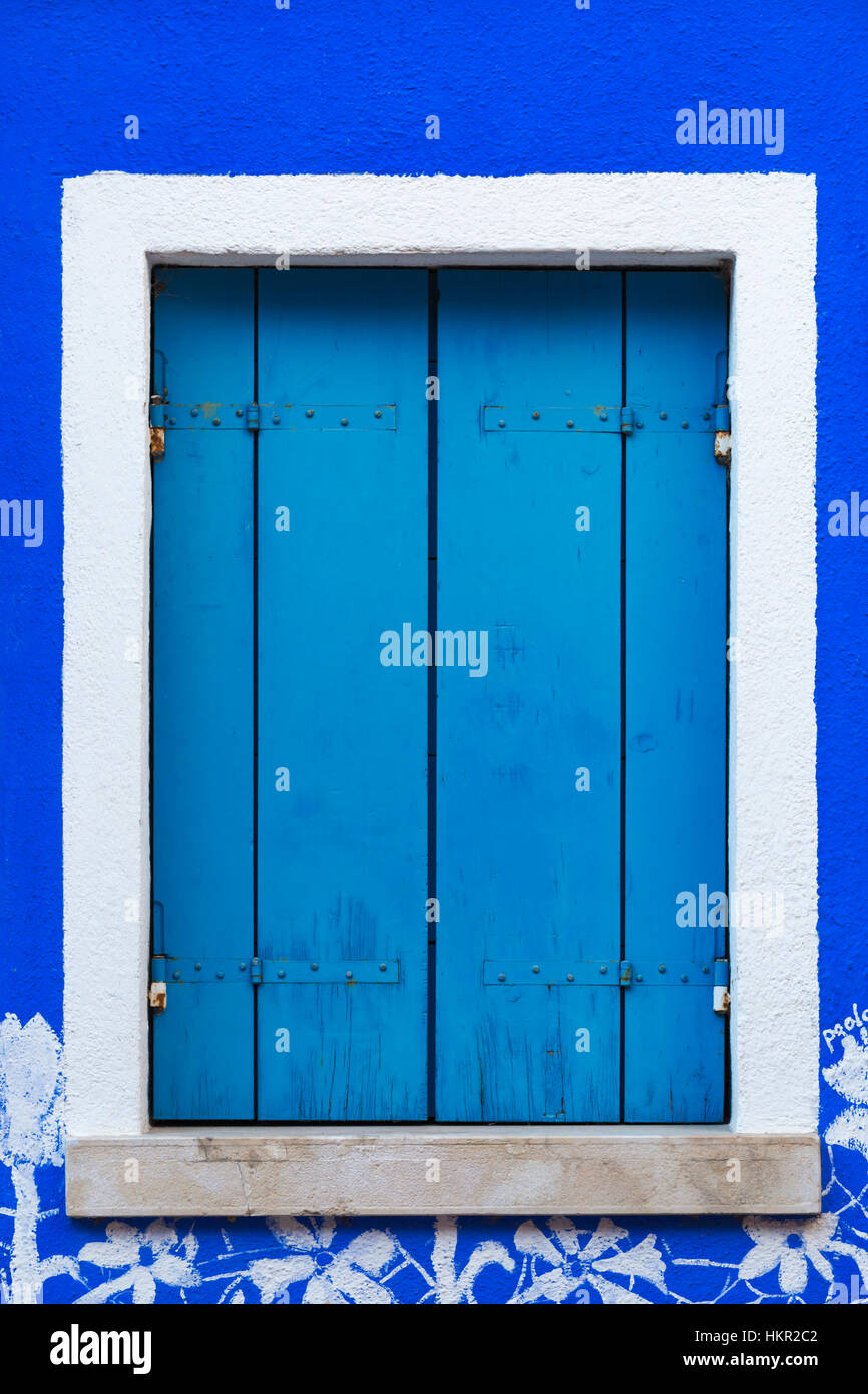 Blue closed wooden window shutters against blue wall of house at Burano ...