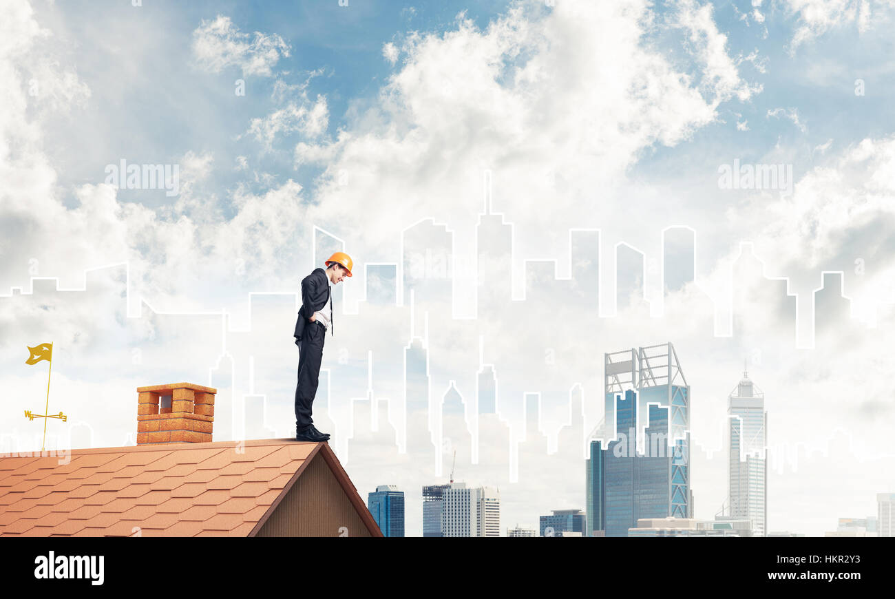 Engineer man standing on roof and looking down. Mixed media Stock Photo ...